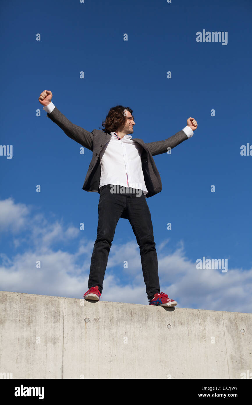 A young male model on a concrete wall with blue sky behind Stock Photo ...