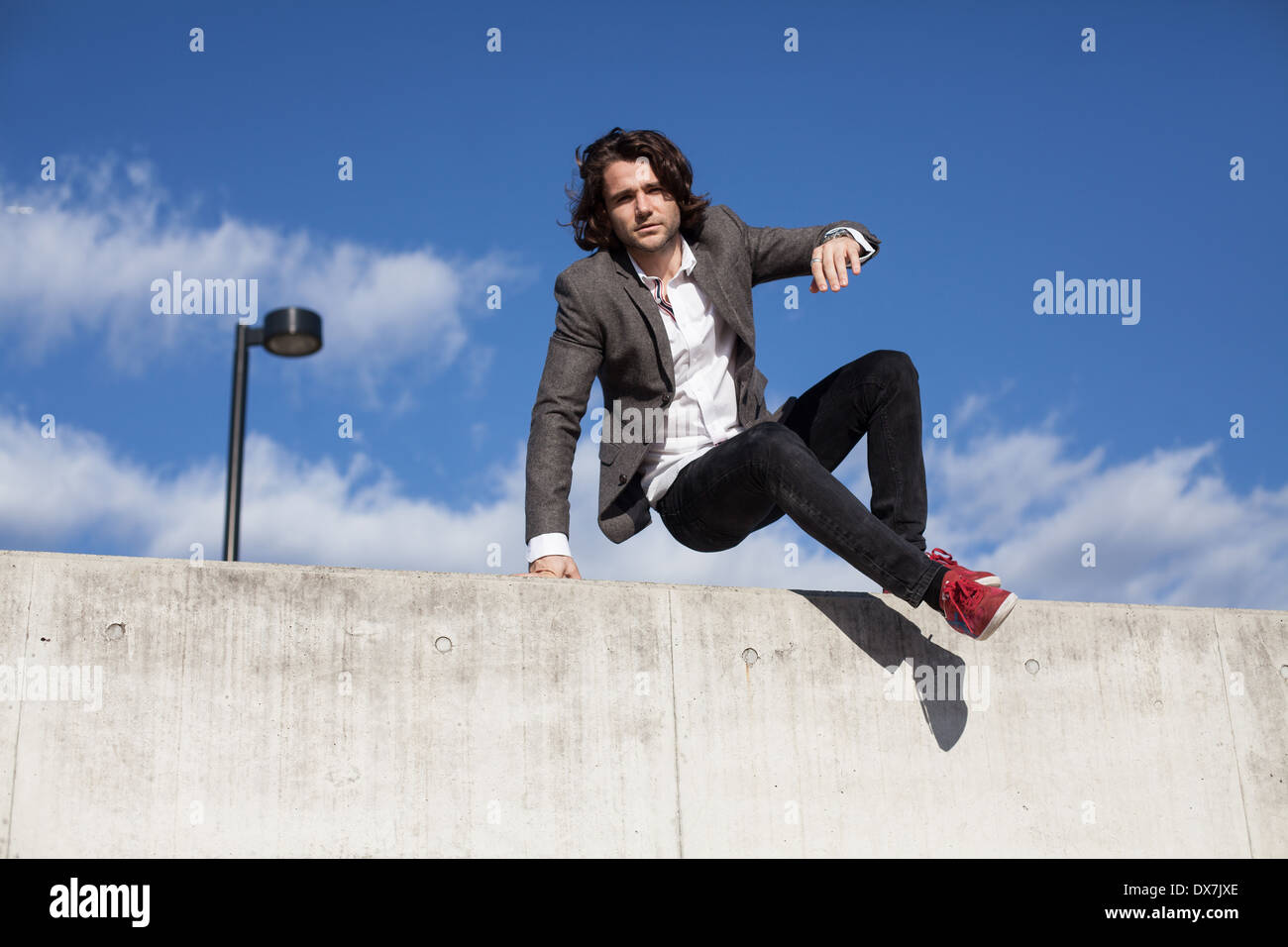 A young male model on a concrete wall with blue sky behind Stock Photo ...