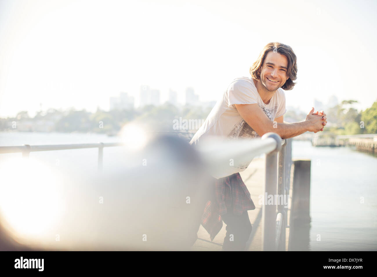 A healthy and happy young man leaning on railings near water Stock ...