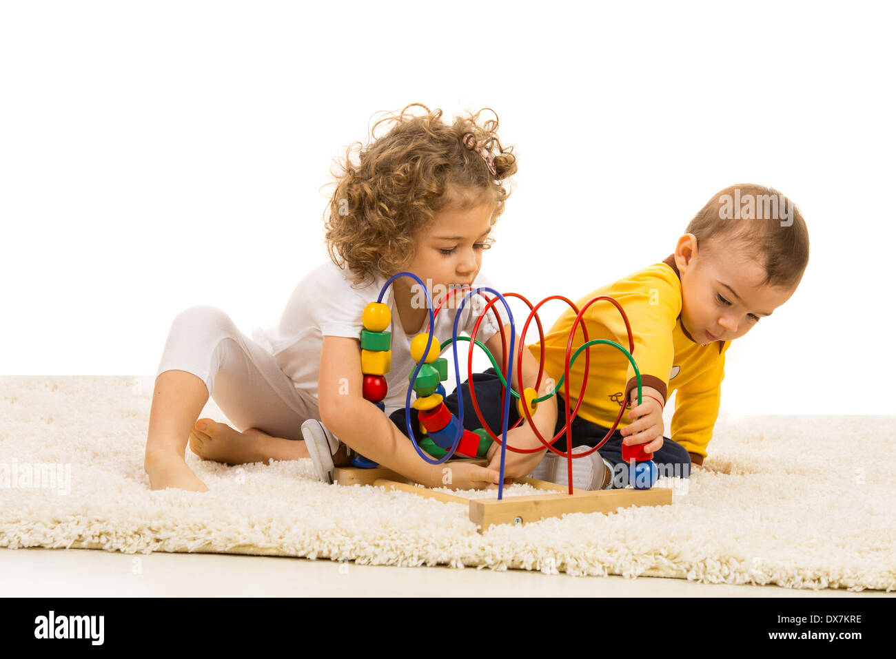 Two kids playing with wooden toy on fur carpet home Stock Photo - Alamy
