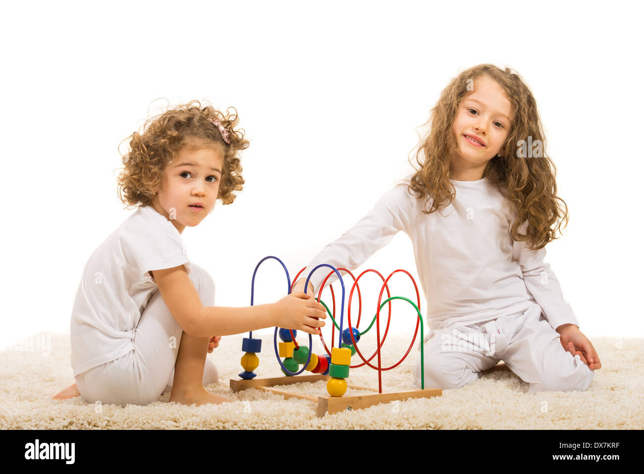 Happy two girls playing with wooden toy home and sitting together on ...