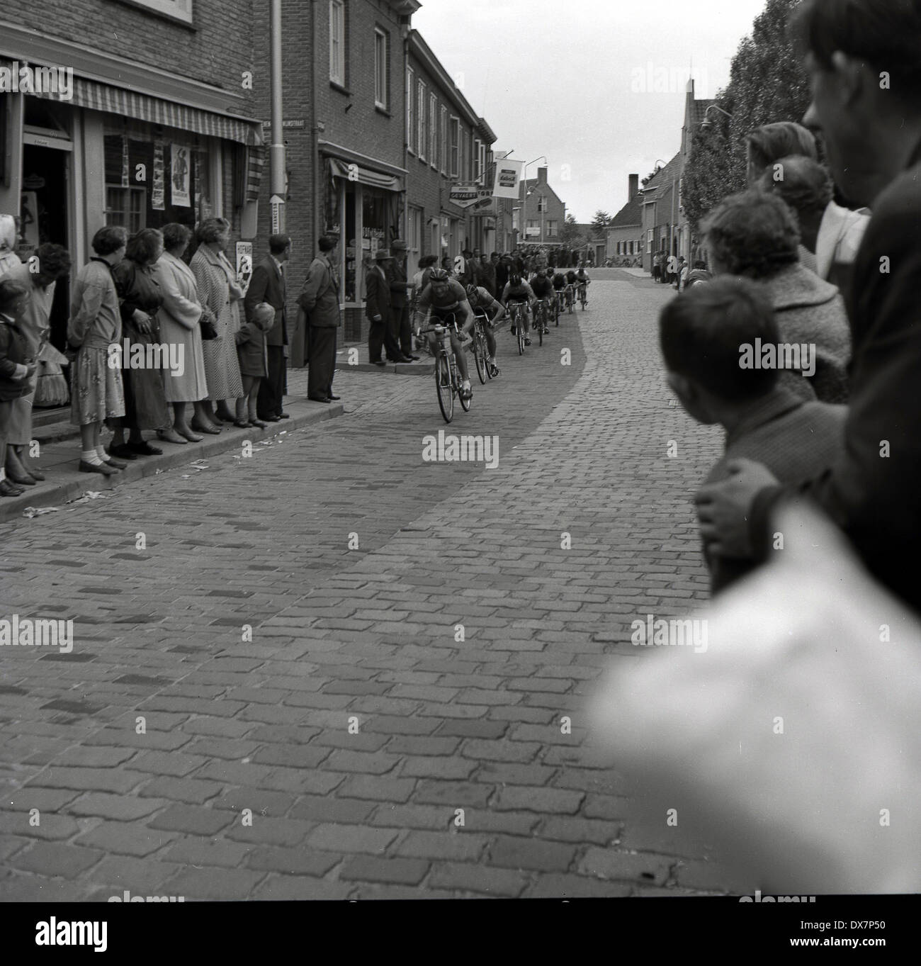 1950s. Historical picture of a cycle race passing through a cobbled ...
