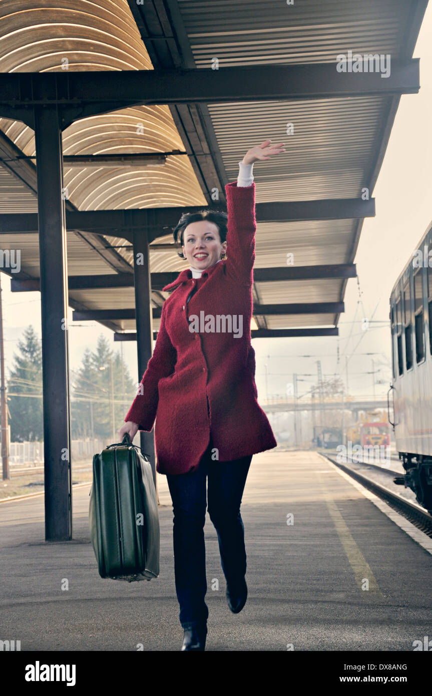 Woman running with suitcase waving Stock Photo - Alamy