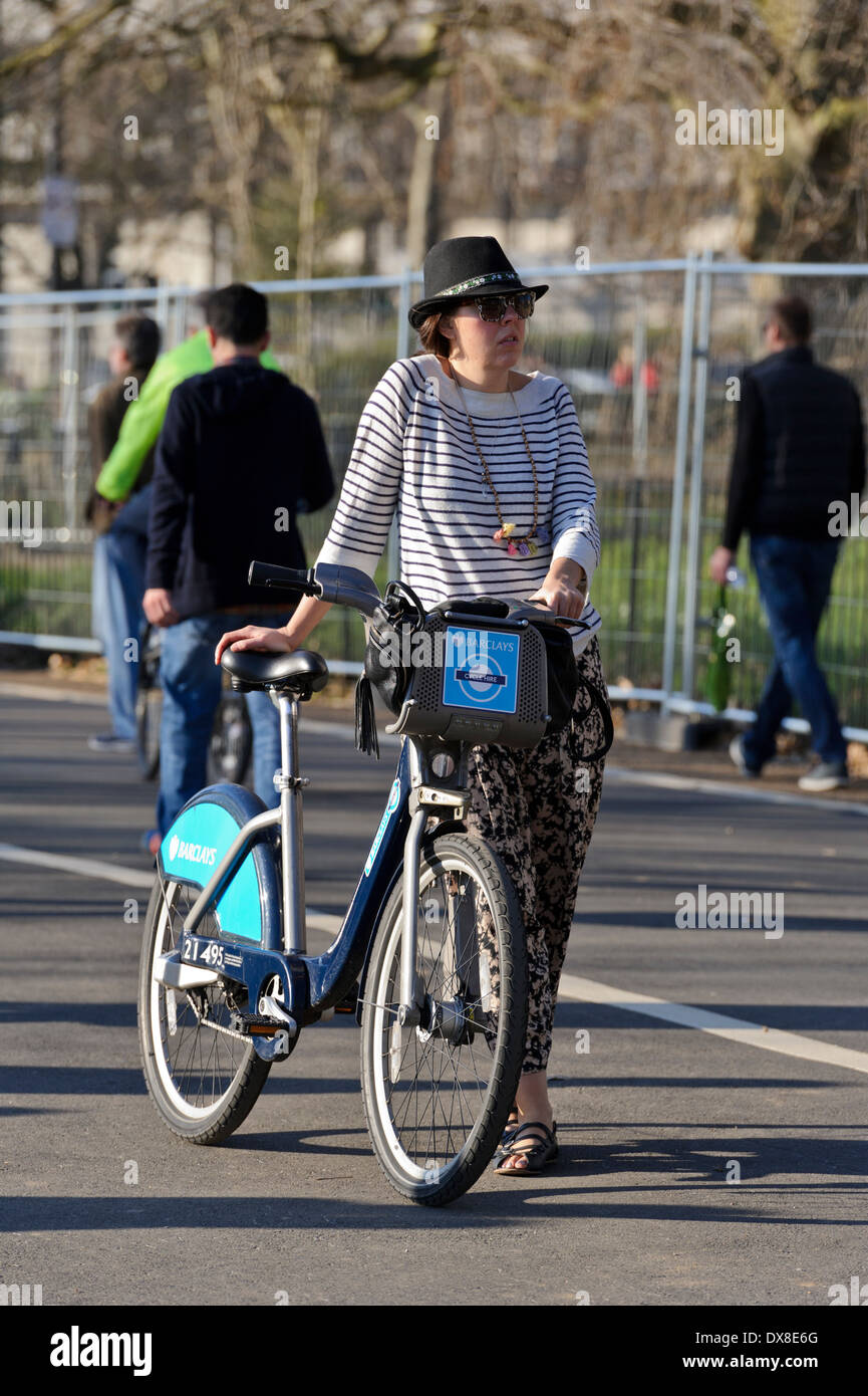 A stylish young woman pushing a bicycle with Barclays logo along the ...