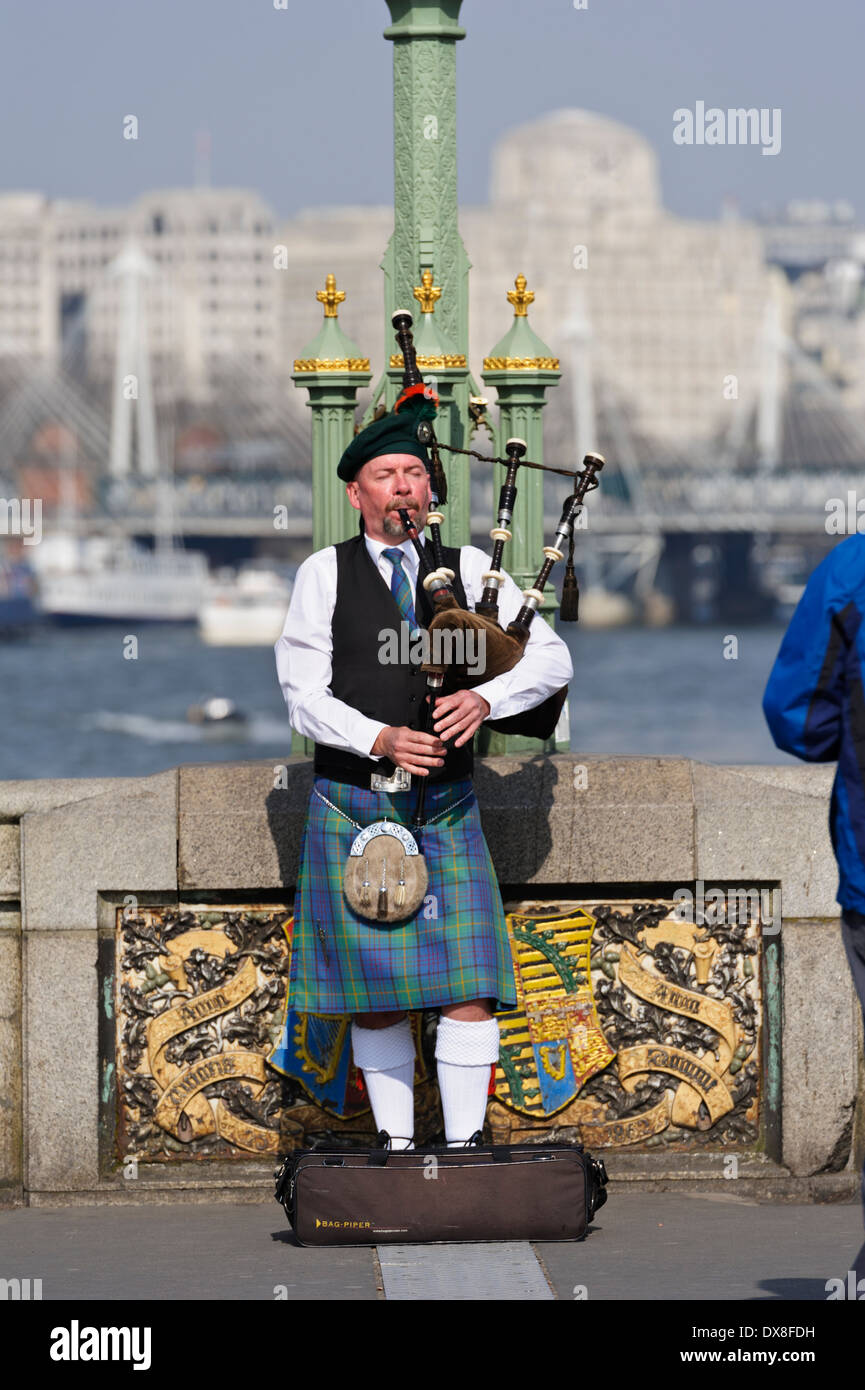 Scottish bagpiper playing music with bagpipe on Westminster bridge ...