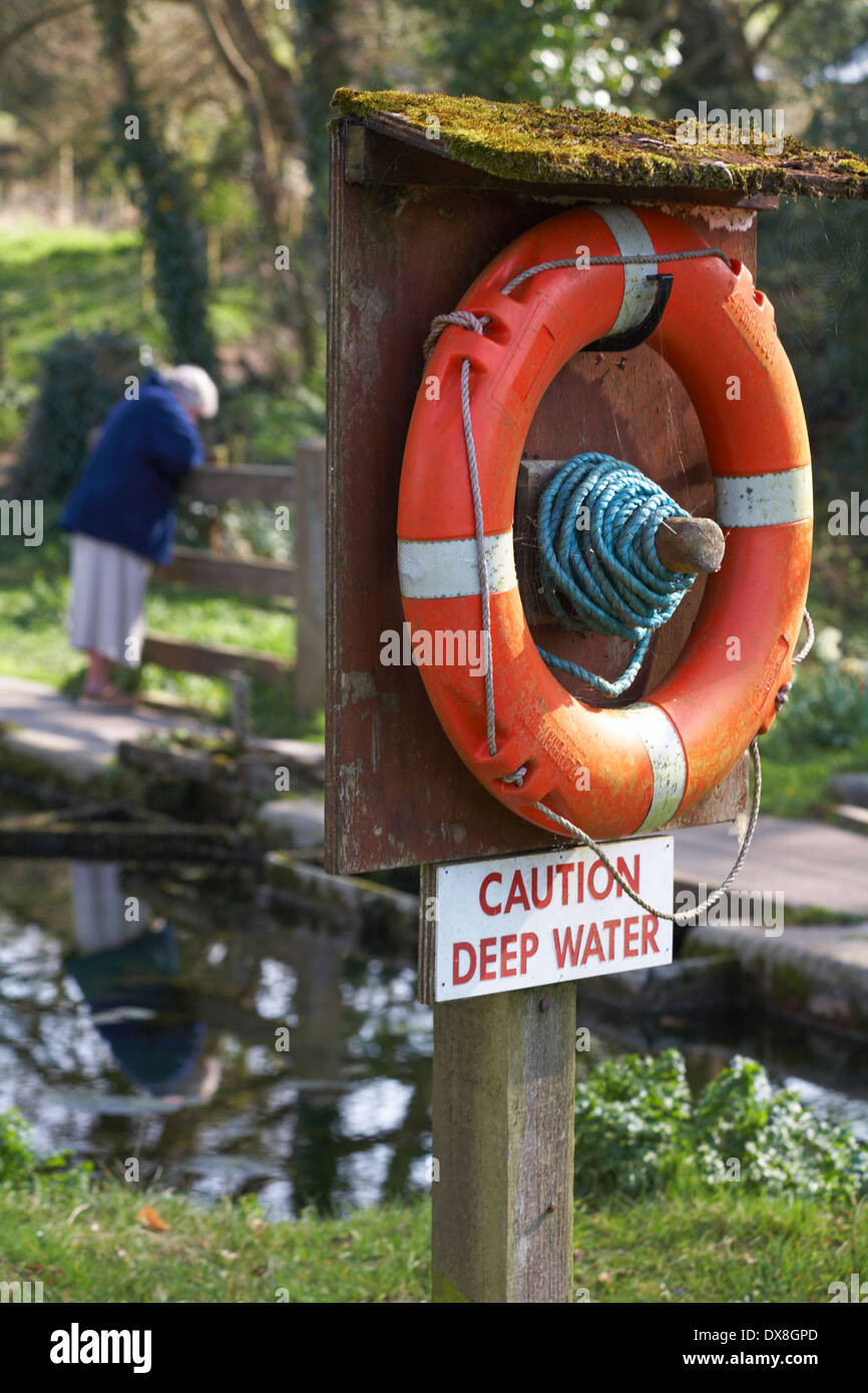 caution deep water sign with women leant over looking at water behind ...
