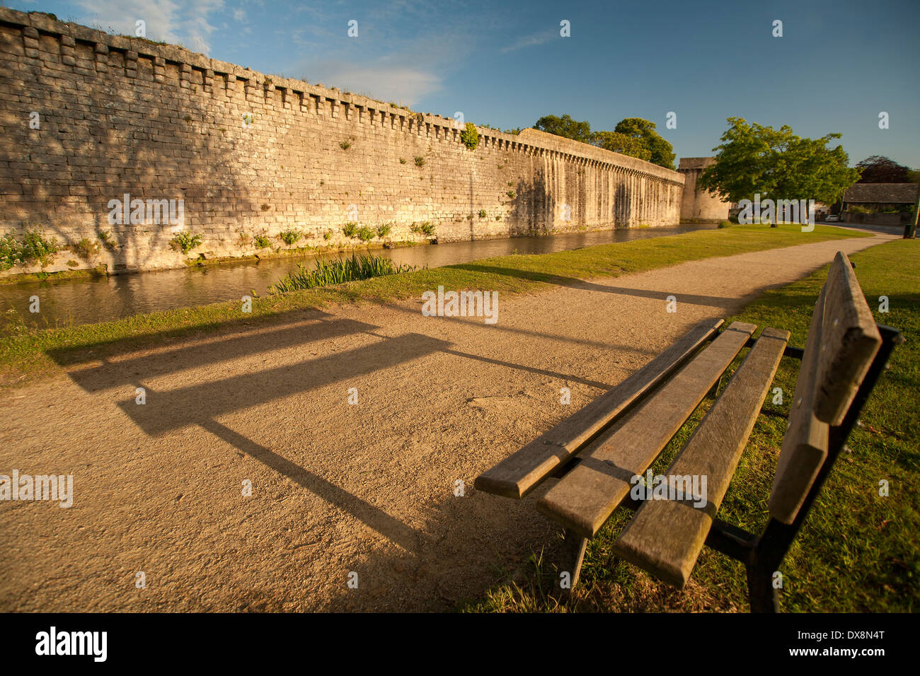 Public bench facing path castle wall and moat Stock Photo - Alamy