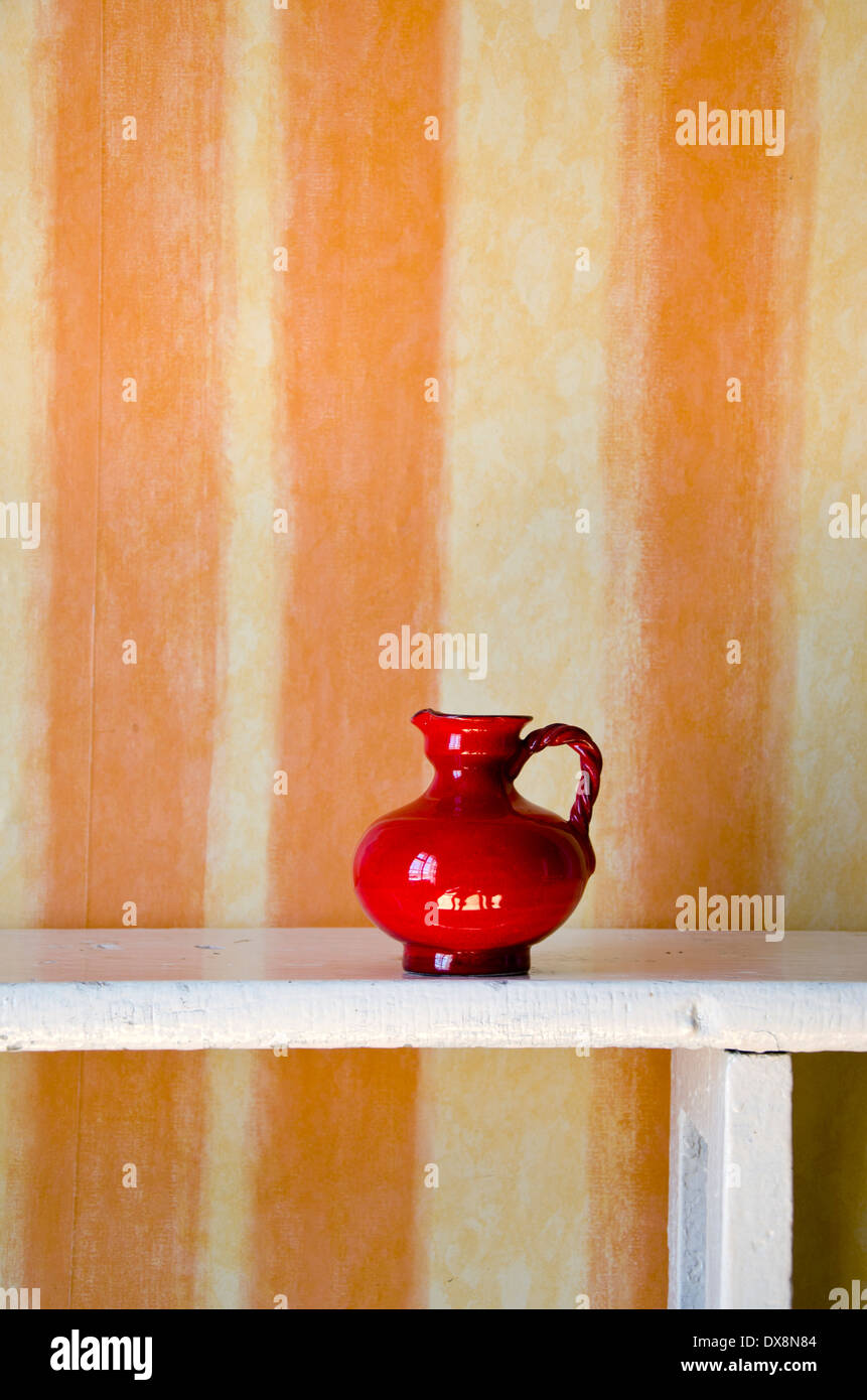 one red ceramic jug on white wooden shelf Stock Photo - Alamy