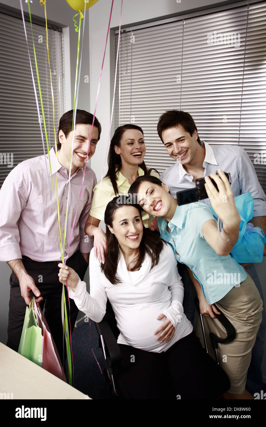 Office colleagues photographing at party with pregnant colleague Stock ...