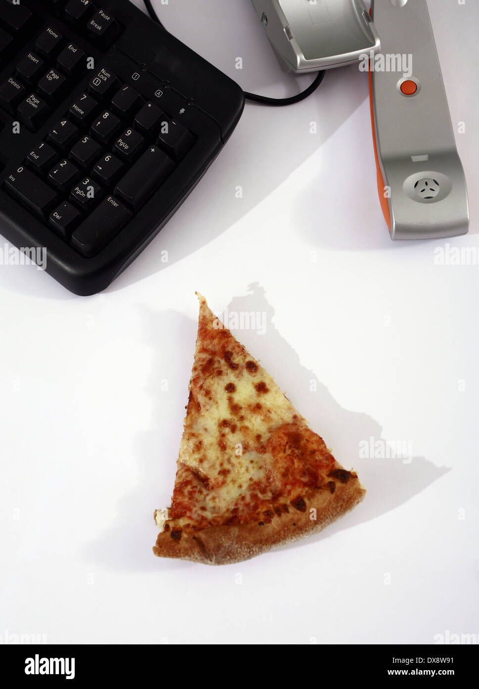 Slice of pizza next to phone on office desk Stock Photo - Alamy
