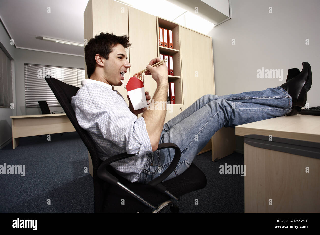 Office worker eating Chinese food at desk Stock Photo - Alamy