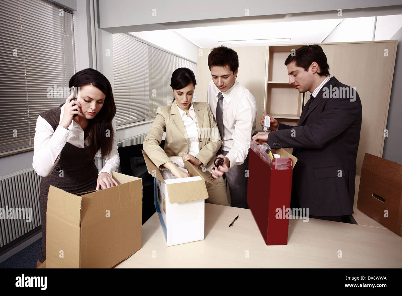 Four business people unpacking boxes in office Stock Photo - Alamy