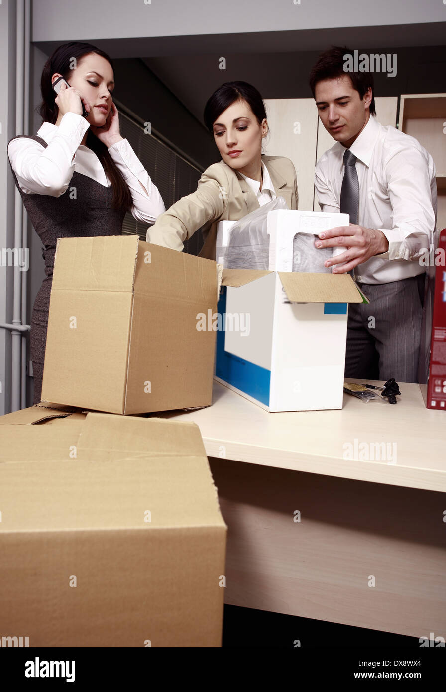 Three business people unpacking boxes in office Stock Photo - Alamy