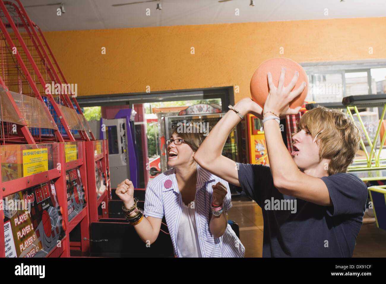 Teenagers playing game in arcade Stock Photo - Alamy