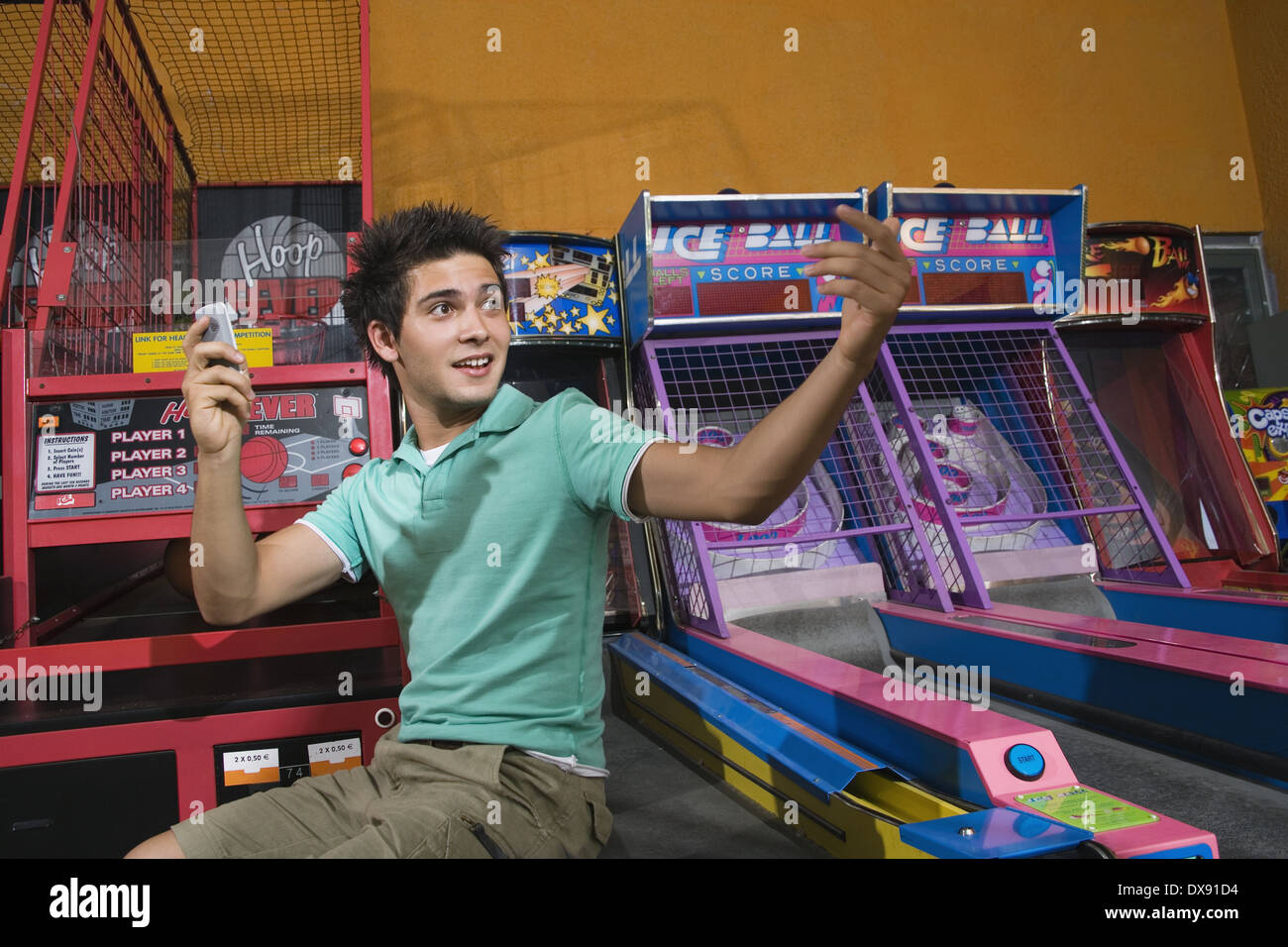 Male teenager with cell phone in arcade Stock Photo - Alamy