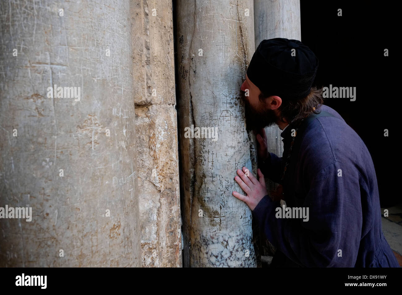 An Orthodox Christian priest kissing the columns which are covered in ...