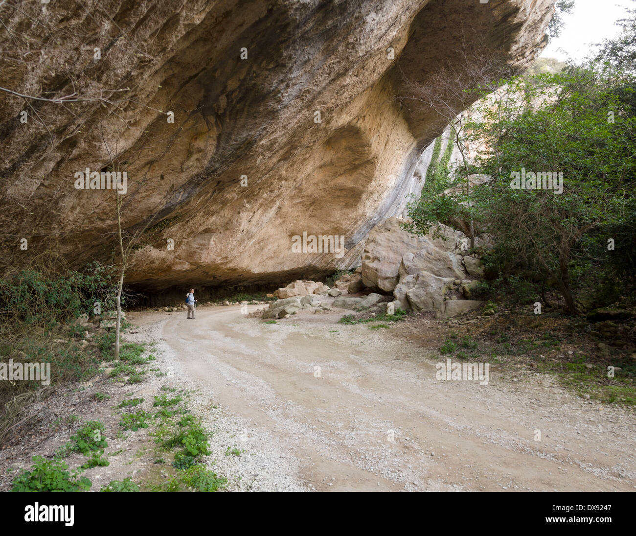 Hiking Under a Rock. A gravel road curves under a huge overhanging rock ...