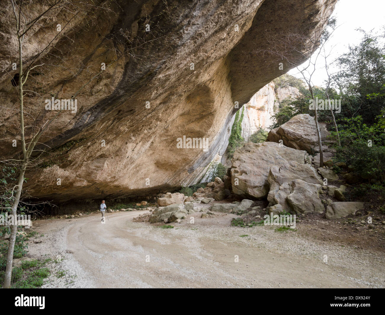 Hiking Under a Rock. A gravel road curves under a huge overhanging rock ...