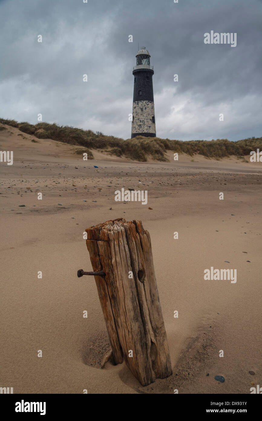 A weathered Post on a beach with Spurn Point Lighthouse in the ...