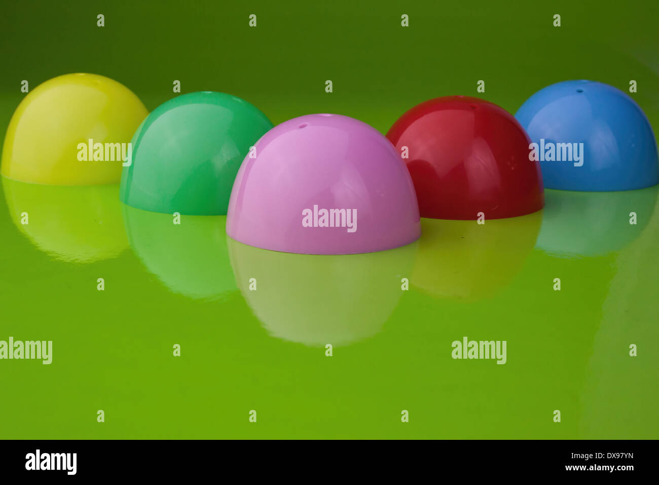 Five half shell plastic Easter egg shells, on a glossy green background ...