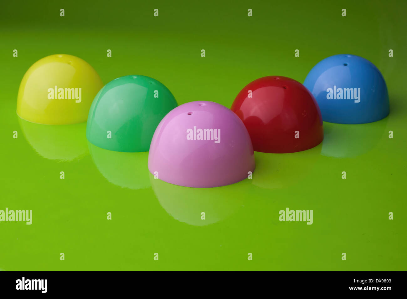 Five half shell plastic Easter egg shells, on a glossy green background ...