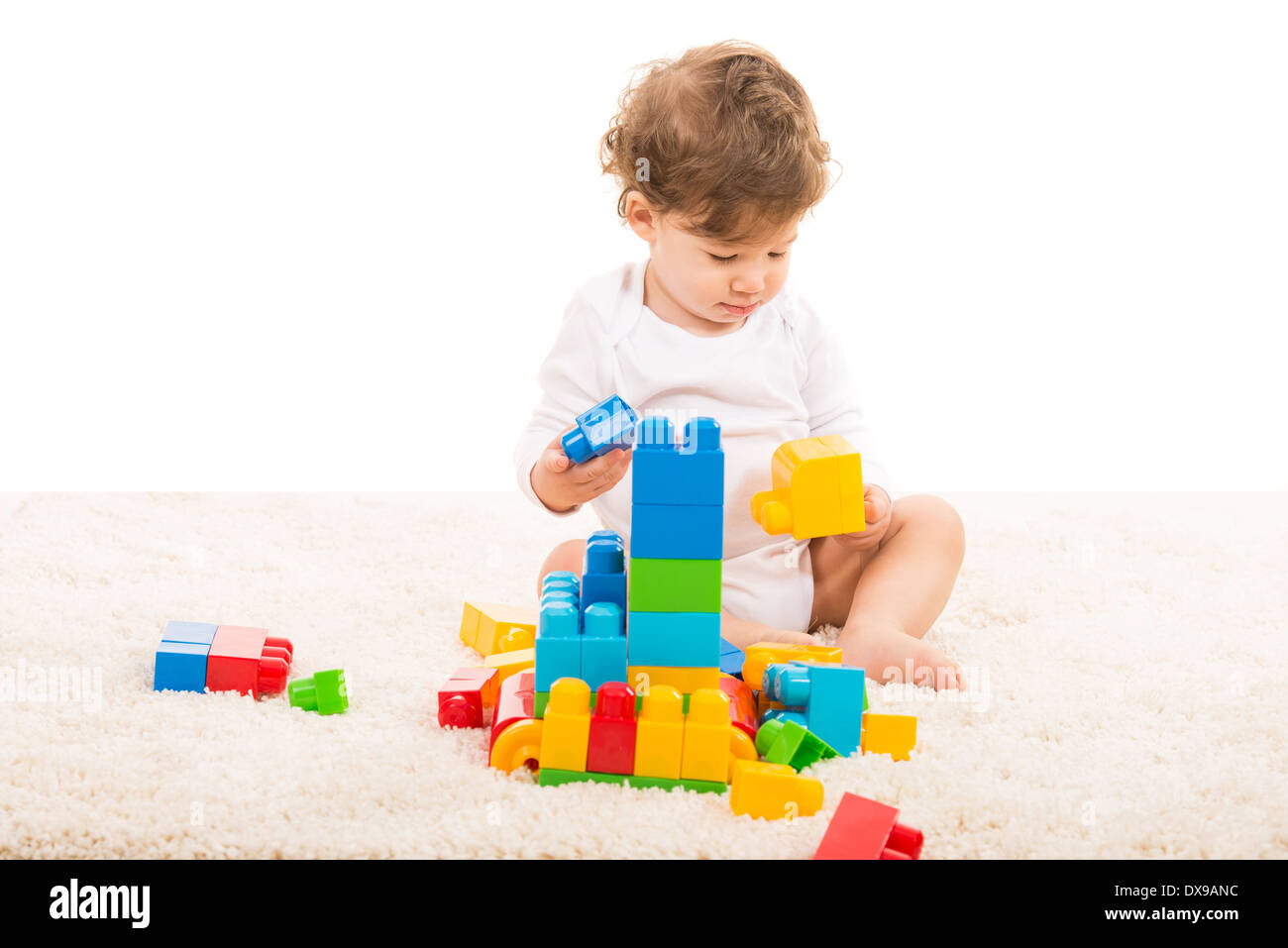 Toddler boy playing with building blocks on carpet against white ...