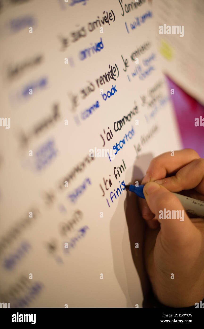 A teenage girl learning verbs writing her GCSE French language school ...
