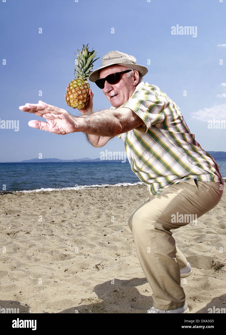 Male senior with pineapple on the beach Stock Photo - Alamy