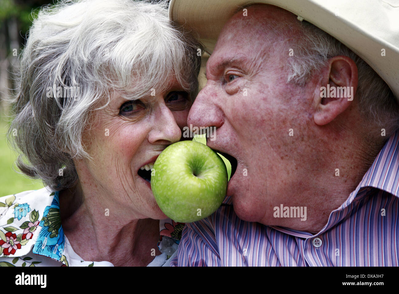 Senior couple both biting apple Stock Photo - Alamy