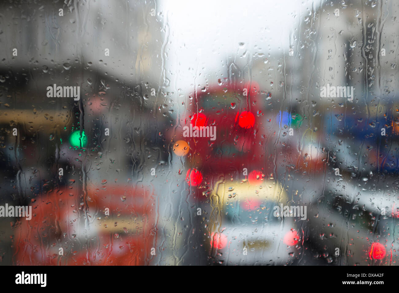 Traffic and a London bus as seen through the rain streaked window of a ...