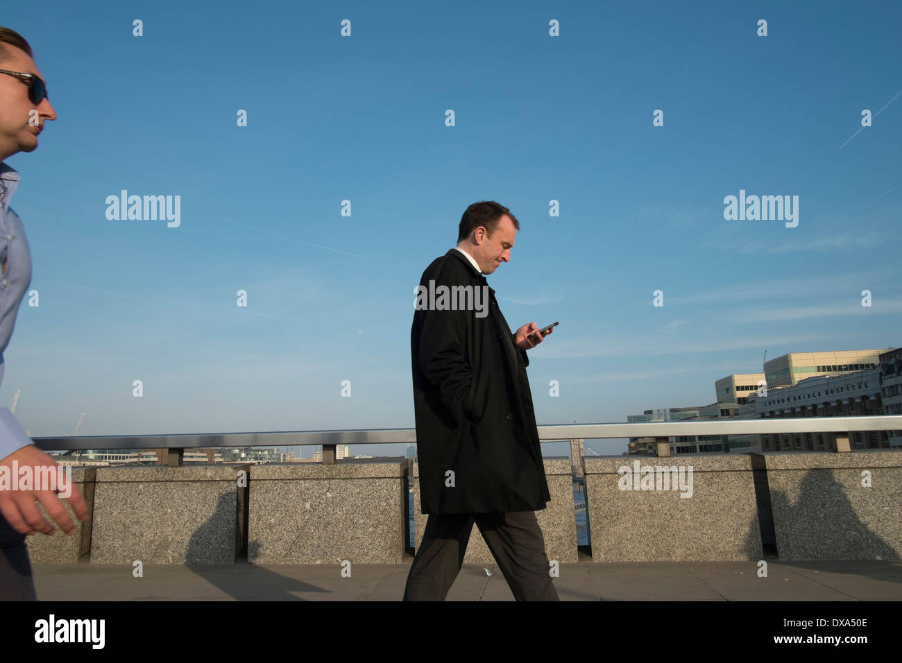 Man checking his mobile phone while crossing London Bridge. London ...