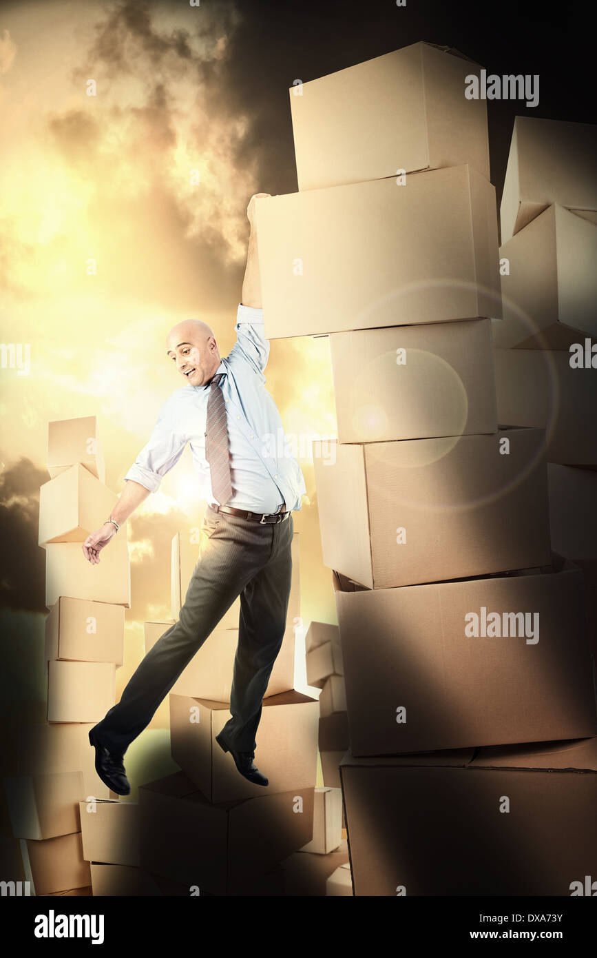 Businessman hanging over a cardboard box cliff Stock Photo - Alamy