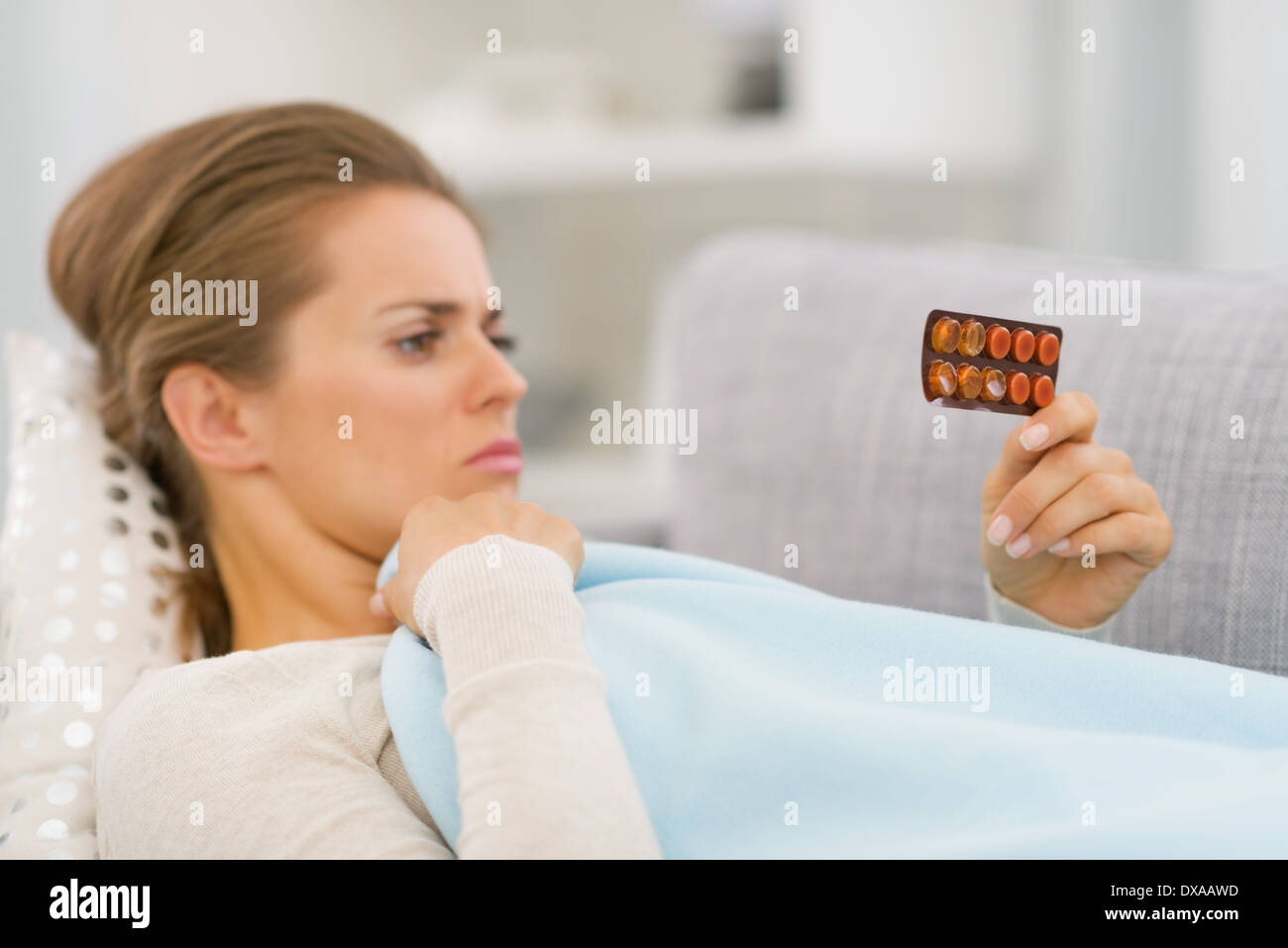 Ill young woman laying on divan and looking on tablets Stock Photo - Alamy