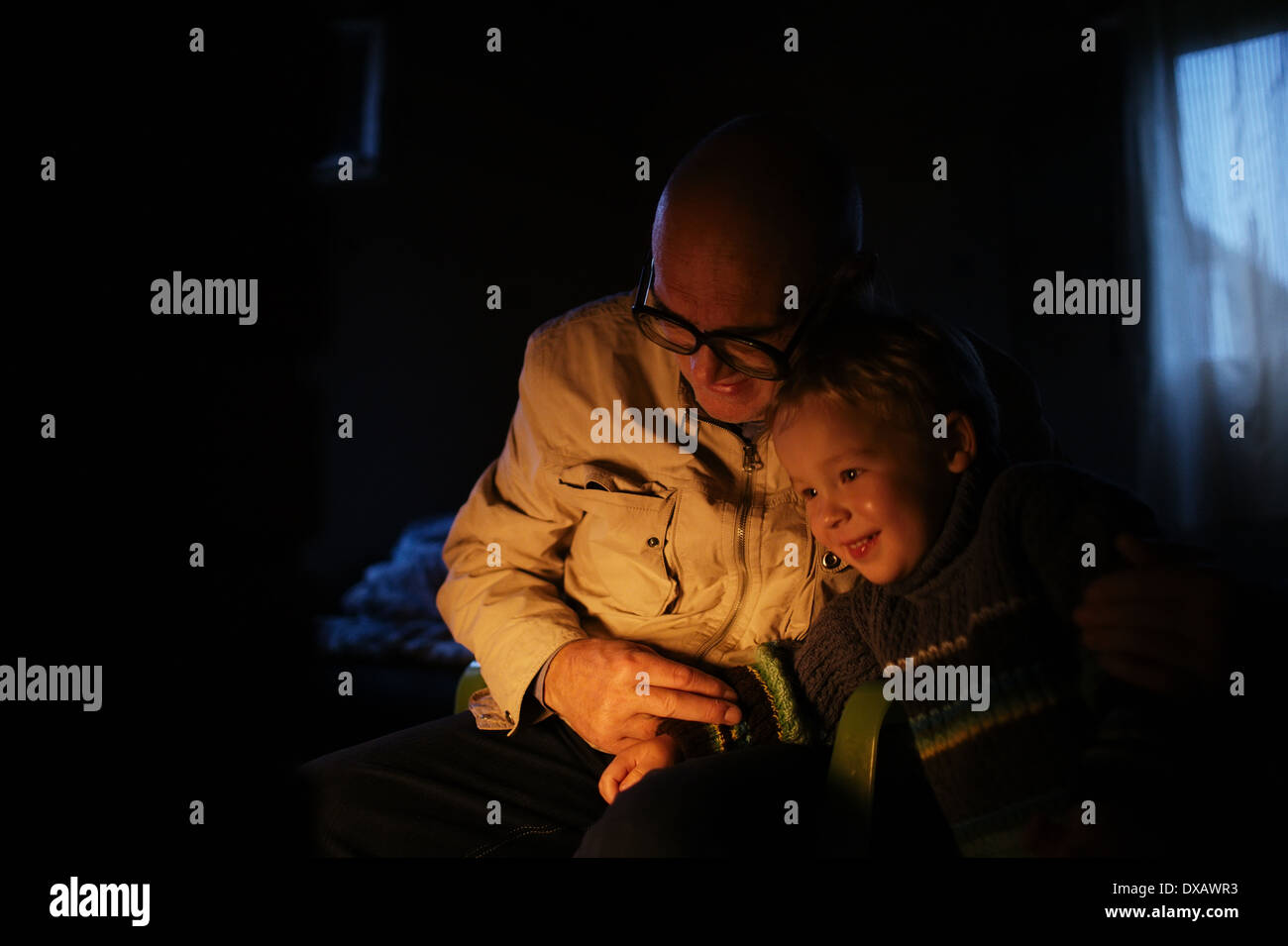 Grandfather hugs his grandson near fireplace at home with fire ...