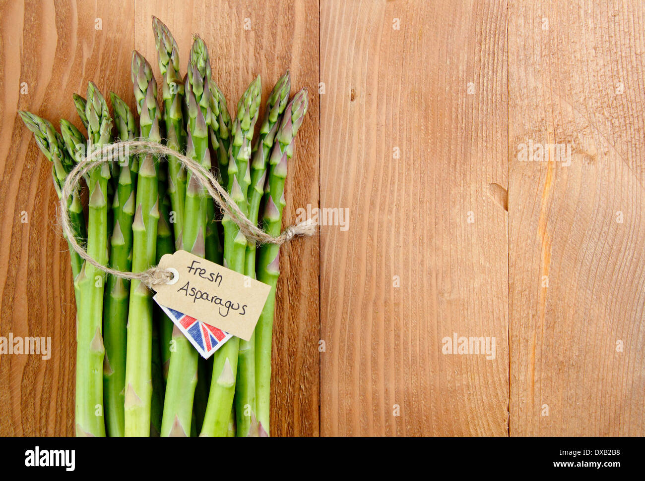A loose bunch of fresh green asparagus stalks with label against rustic ...