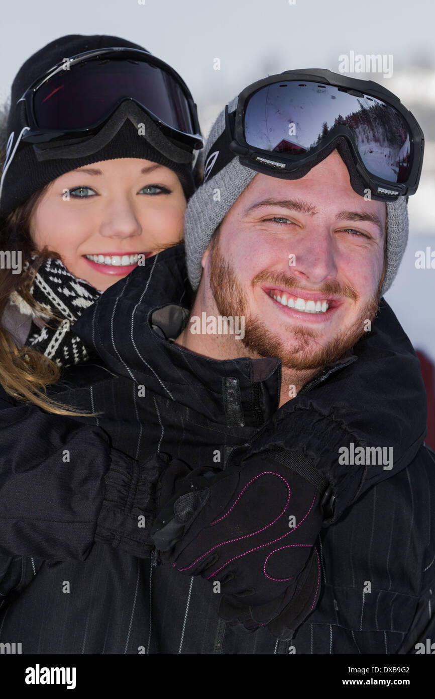 beautiful young couple wearing snow gear playing outside on the snowy ...