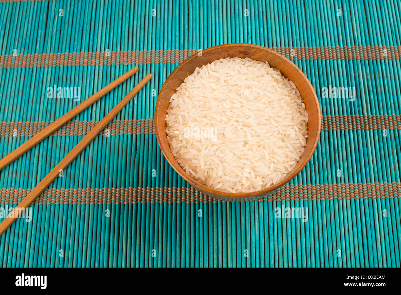 A bowl with raw rice and chopsticks on a bamboo mat Stock Photo - Alamy