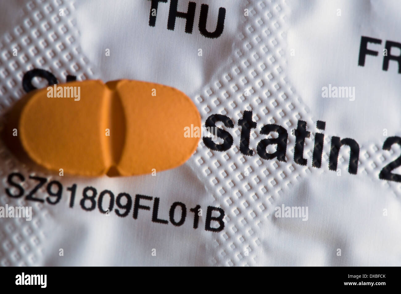 A statin tablet against a blister pack with the word Statin showing ...