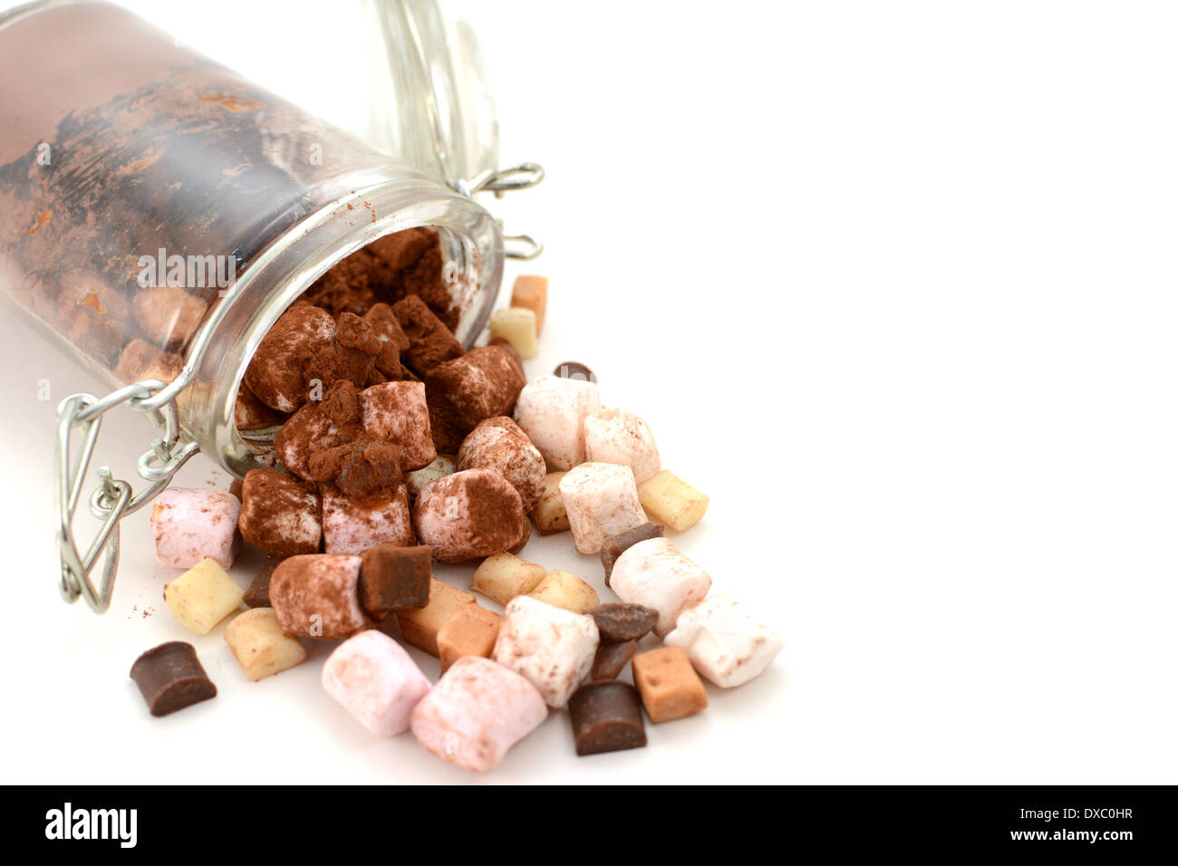Cocoa and hot chocolate toppings spill from a glass jar with copy space ...