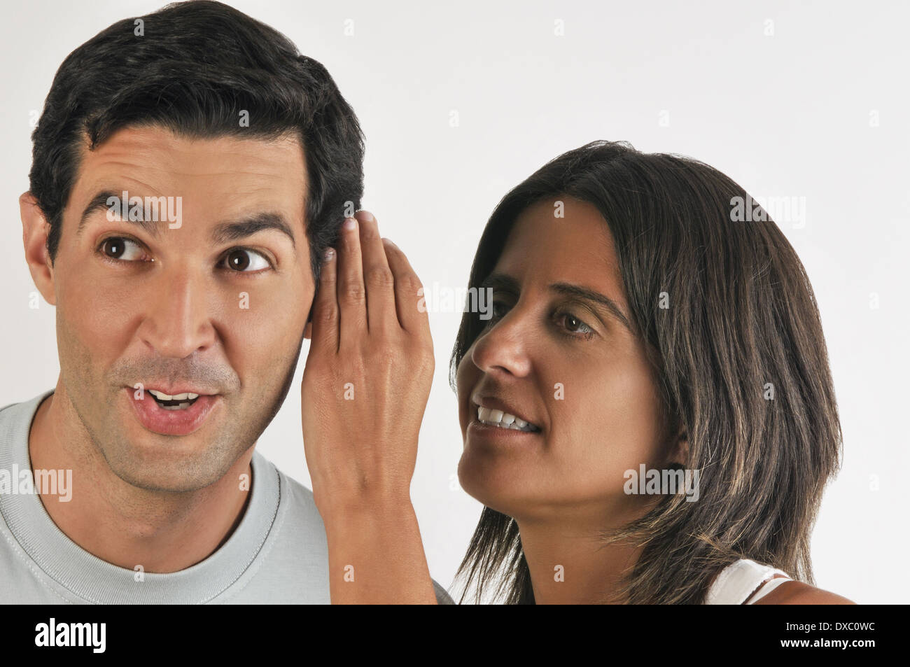Female young adult whispering in man's ear Stock Photo - Alamy