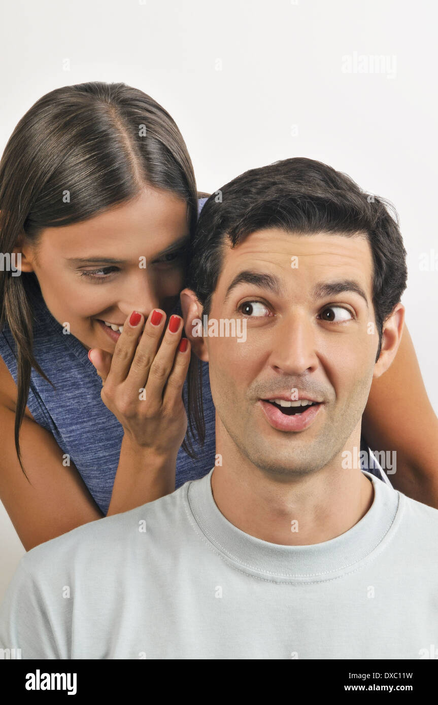 Female young adult whispering in man's ear Stock Photo - Alamy
