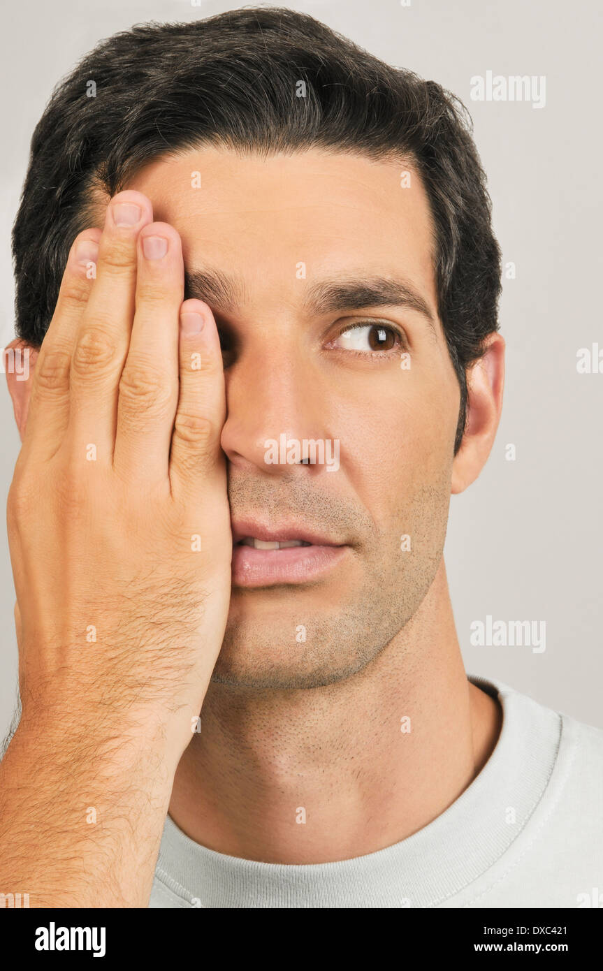 Young male adult, hand covering one eye Stock Photo - Alamy