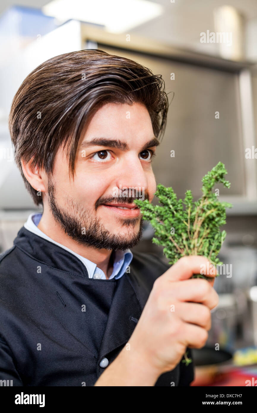 Chef checking the freshness of a bunch of fresh herbs by smelling the ...
