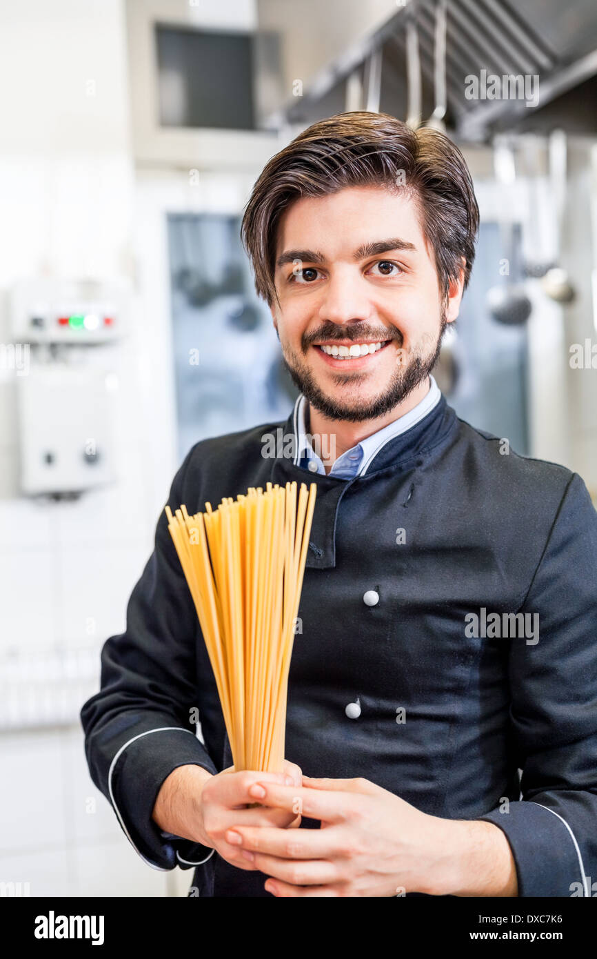Attractive friendly chef or cook in uniform preparing spaghetti pasta ...