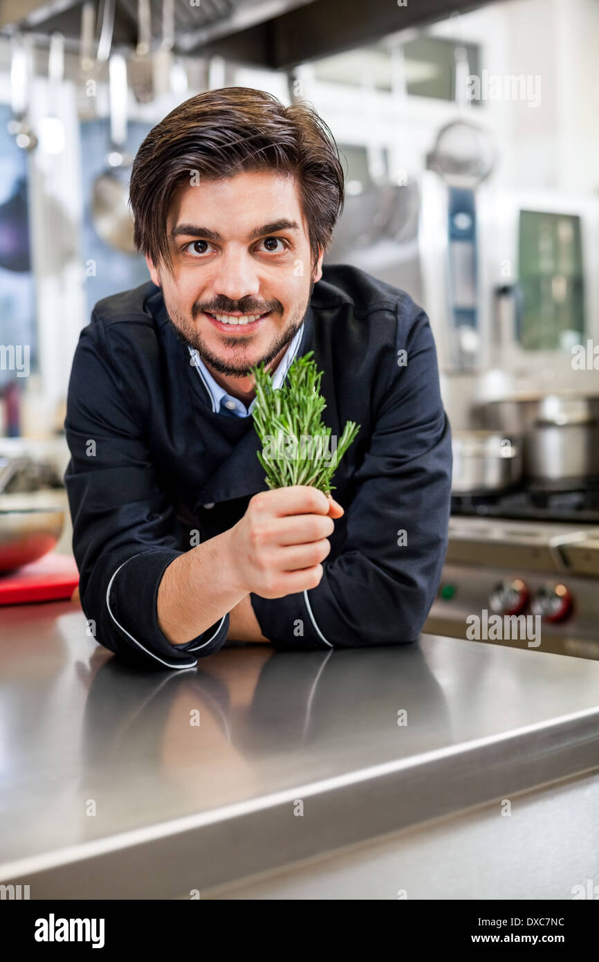 Chef checking the freshness of a bunch of fresh herbs by smelling the ...