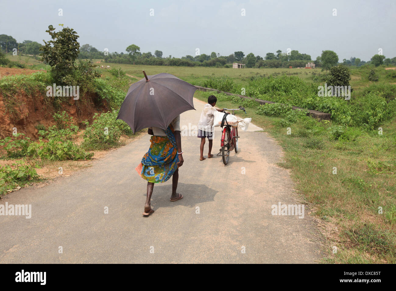 Grandmother walking and grandson pushing cycle on way to weekly market ...