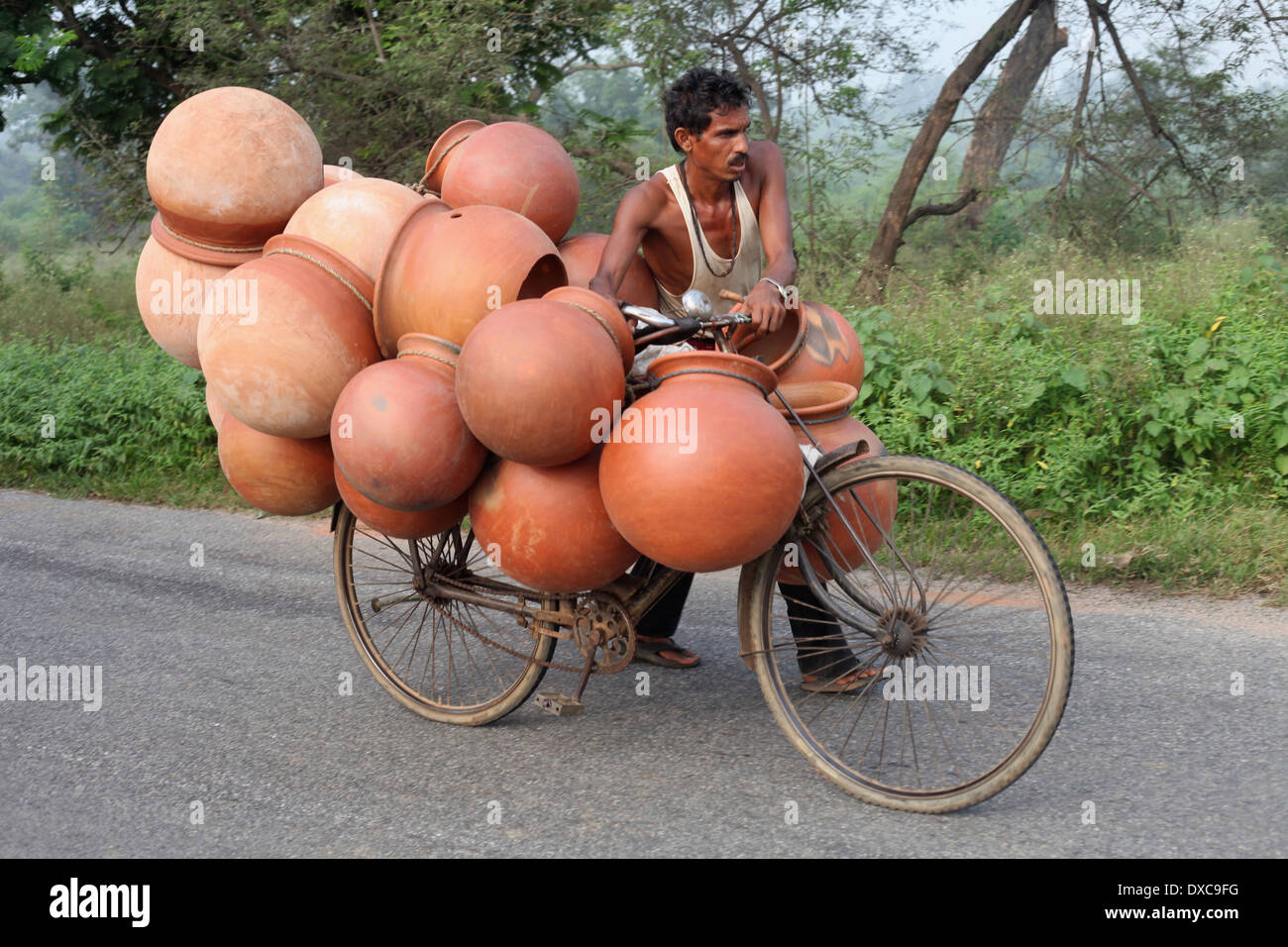Tribal man carrying pots to the market on a bicycle. Kurmali tribe ...