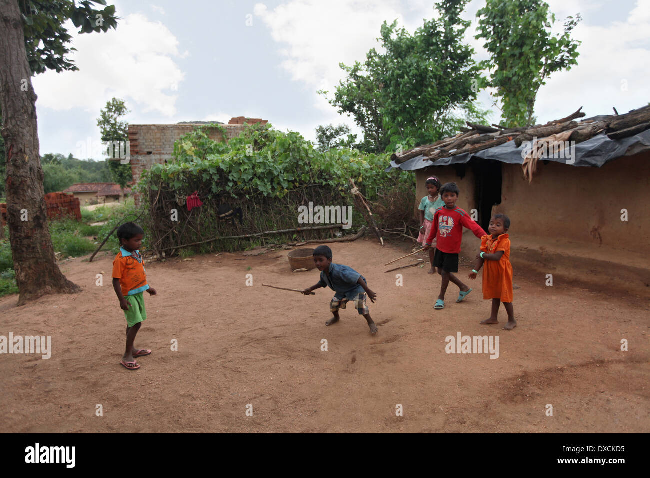 Tribal children playing gulli-danda in courtyard of a house. Malhar ...