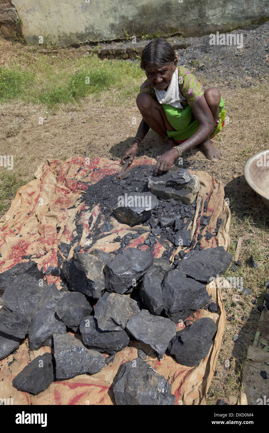 Lady breaking coal in pieces for transport to households as a source of ...