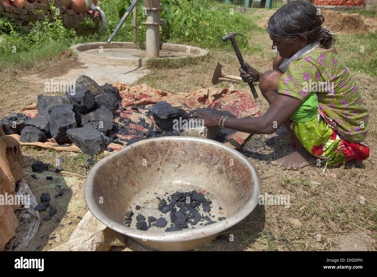 Lady breaking coal in pieces for transport to households as a source of ...